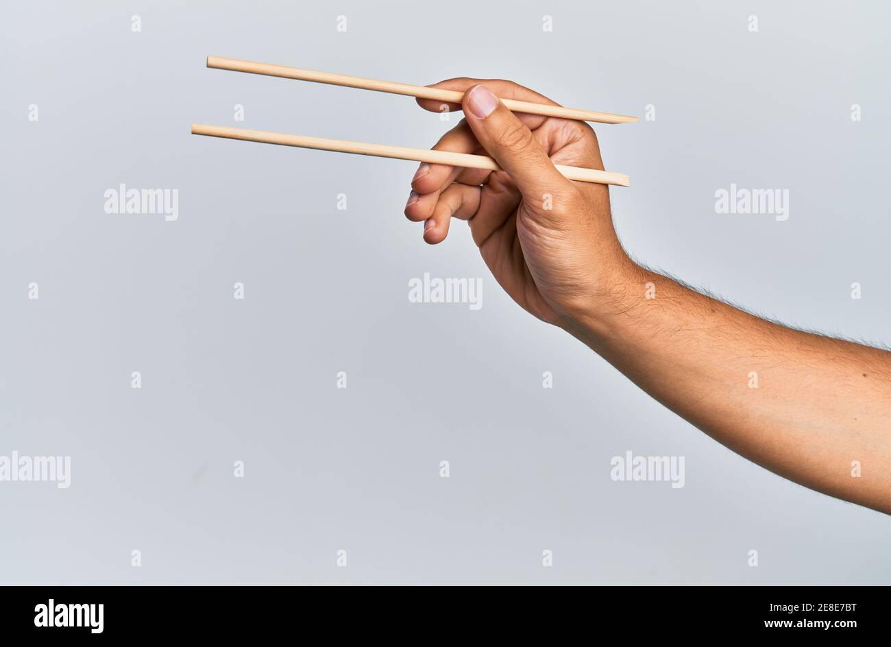 Hand of hispanic man holding wooden chopsticks over isolated white ...