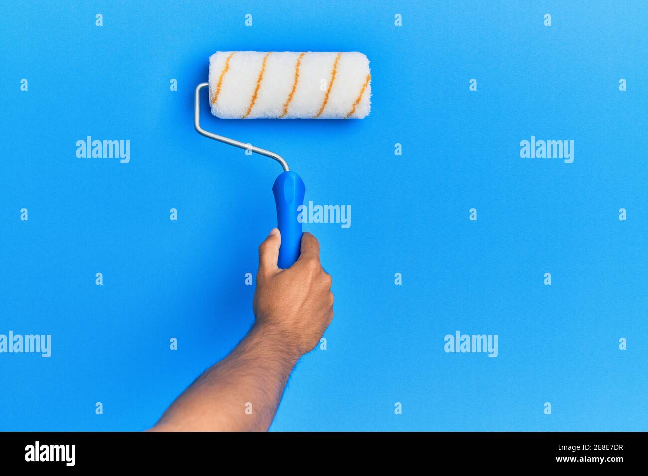 Hand of hispanic man painting blue wall using paint roller Stock Photo ...