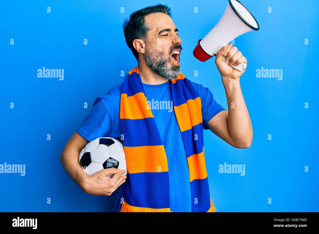 Middle age man with beard and grey hair football hooligan holding ball ...