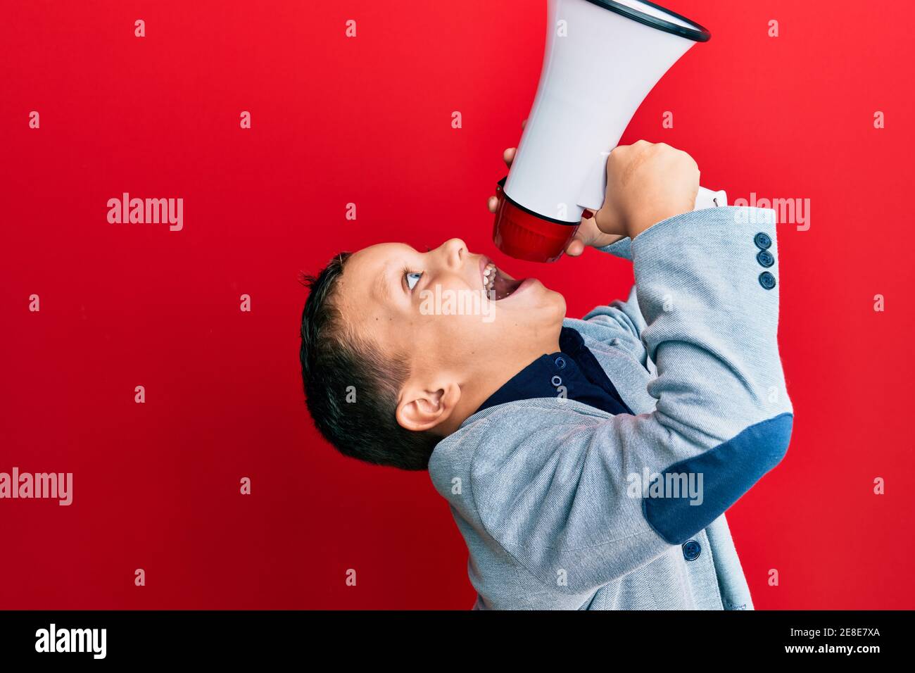 Adorable caucasian boy screaming using megaphone over isolated red ...