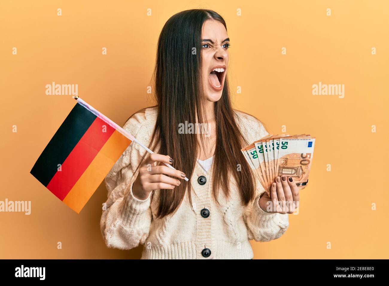 Beautiful brunette young woman holding germany flag and euros banknotes ...