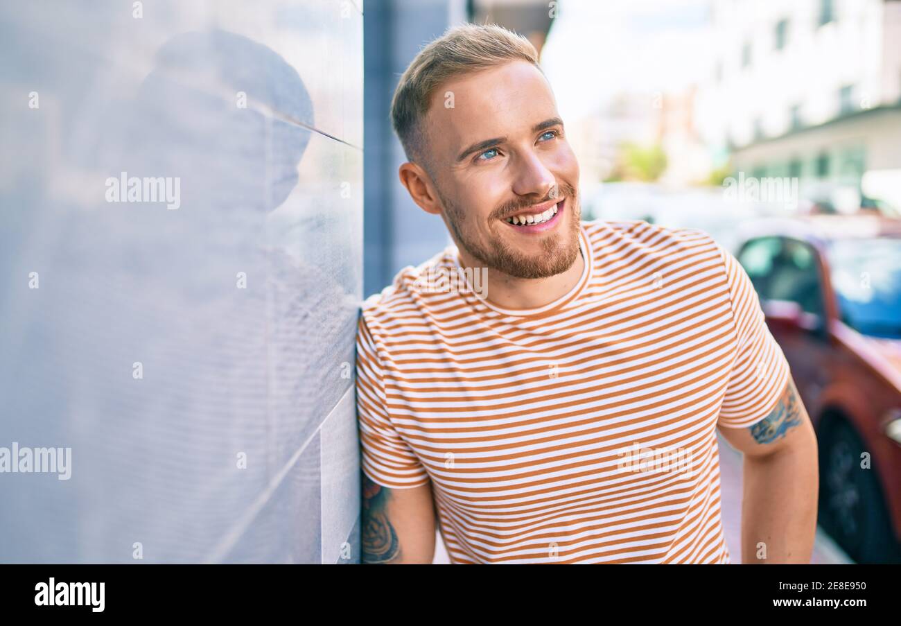 Young irish man smiling happy leaning on the wall at street of city ...