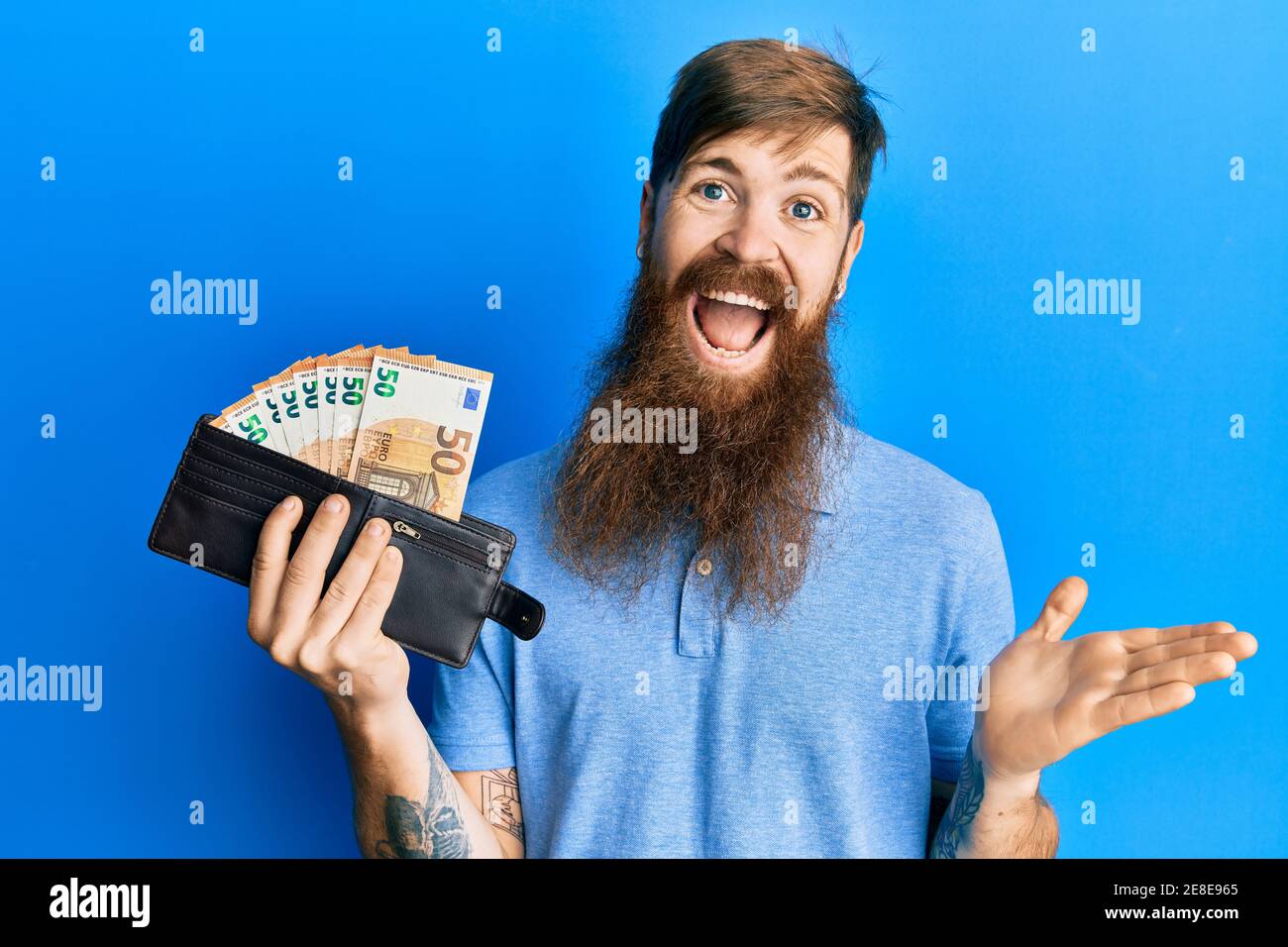 Redhead man with long beard holding wallet euro banknotes celebrating ...