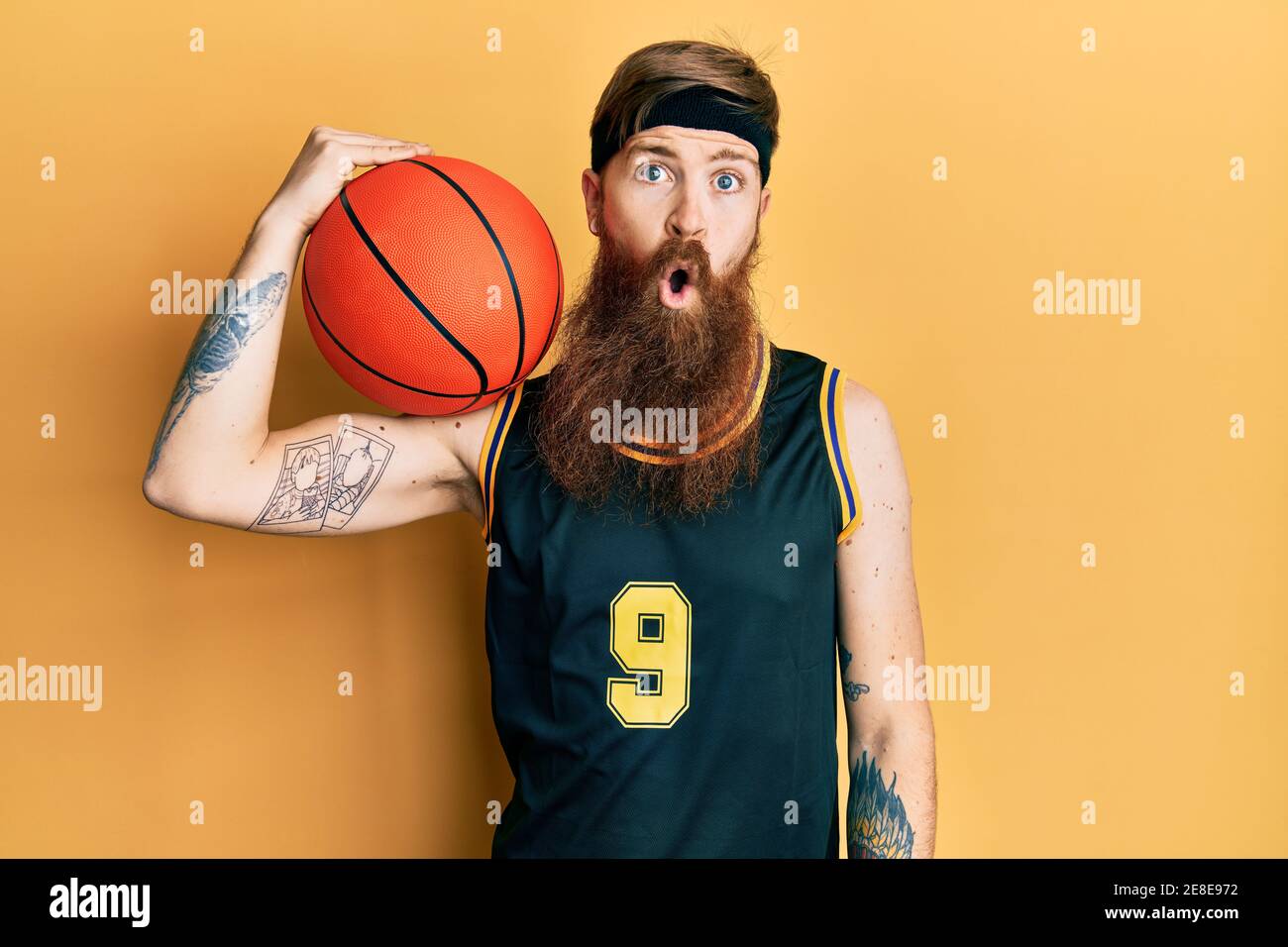 Redhead Man With Long Beard Wearing Basketball Uniform Holding Ball