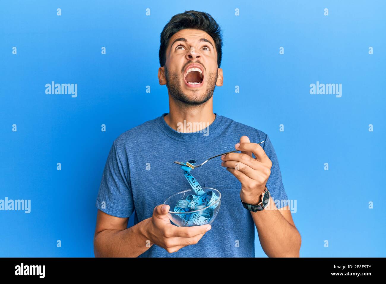 Young handsome man eating measure meter doing diet for weight loss ...