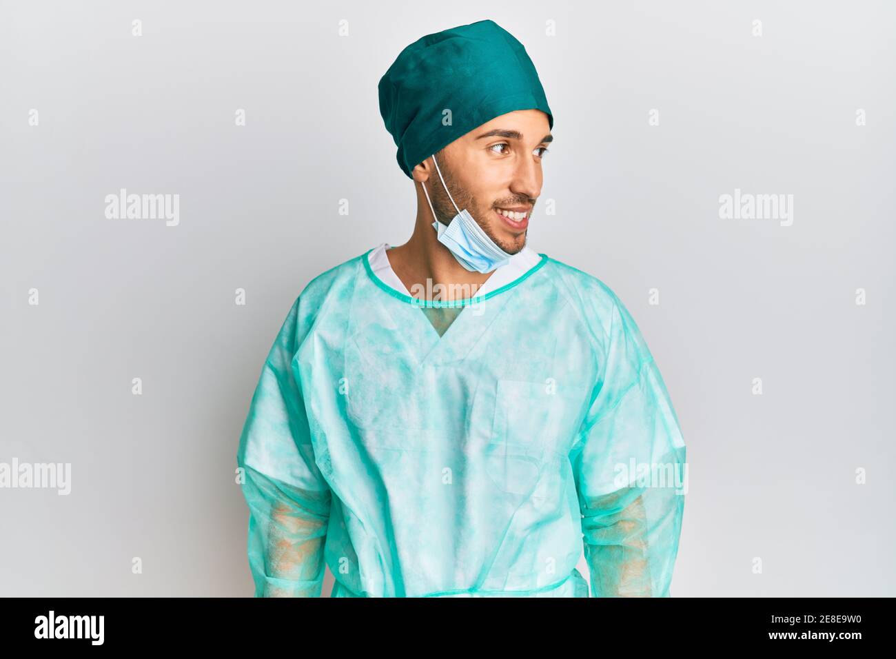 Young handsome man wearing surgeon uniform and medical mask looking to ...