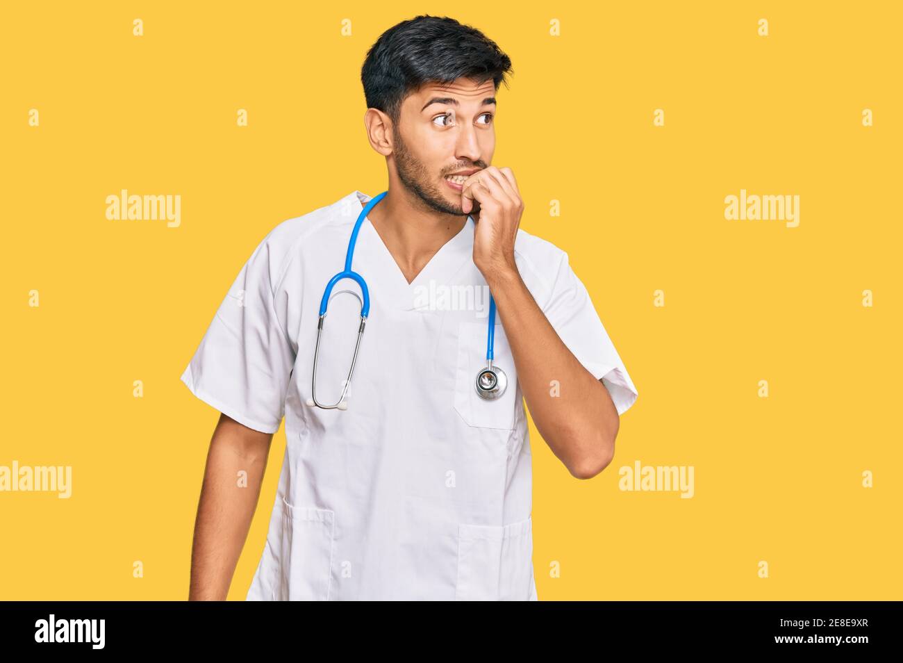 Young handsome man wearing doctor uniform and stethoscope looking ...