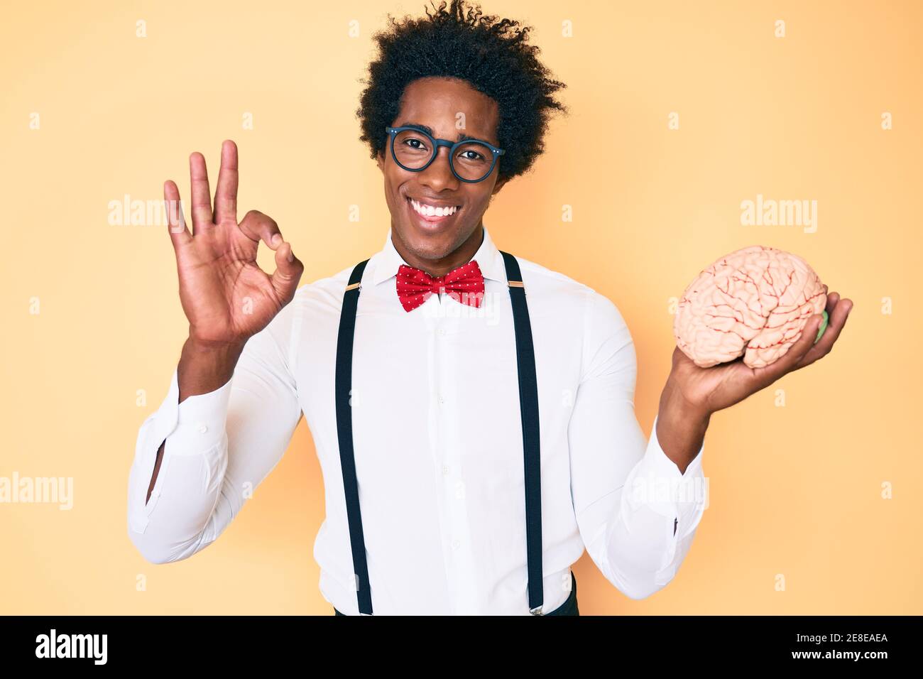 Handsome african american nerd man with afro hair holding brain doing ...