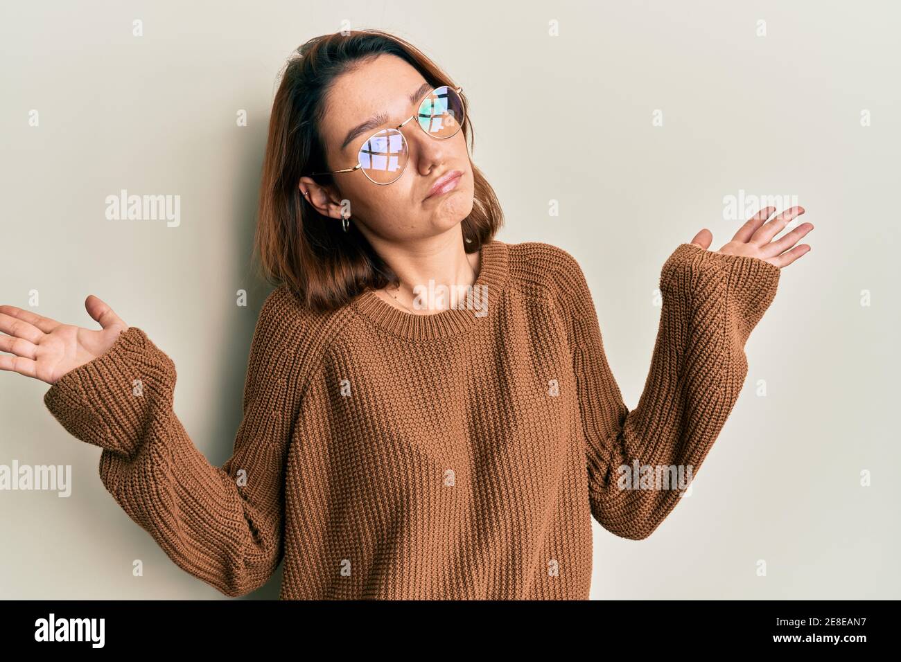 Young caucasian woman wearing casual clothes and glasses clueless and ...