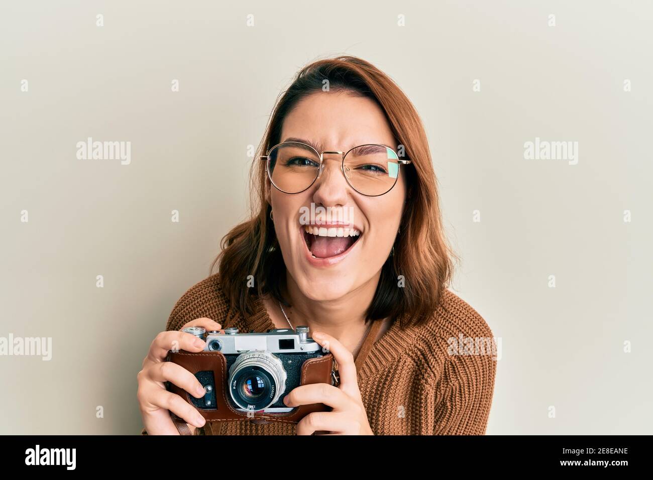 Young caucasian woman holding vintage camera smiling and laughing hard ...
