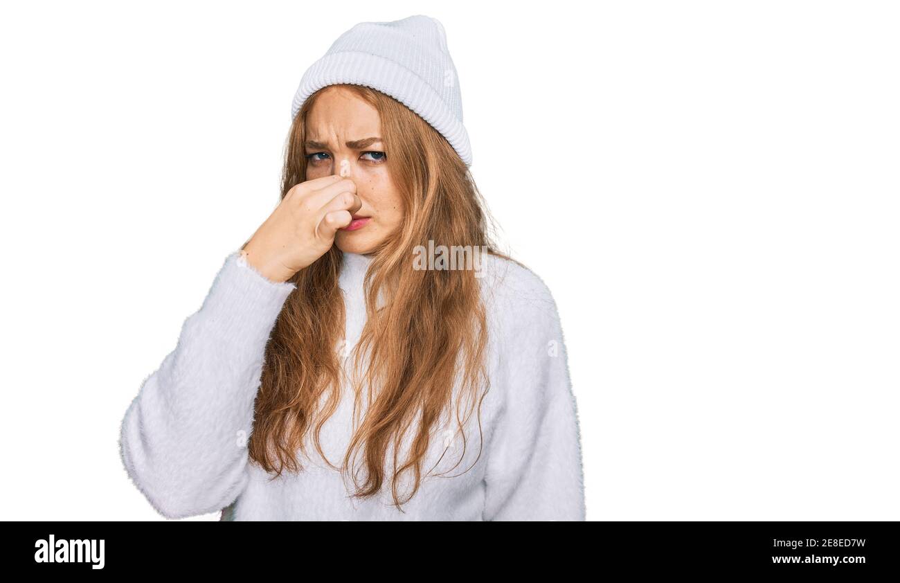 Young caucasian girl wearing wool sweater and winter cap smelling ...