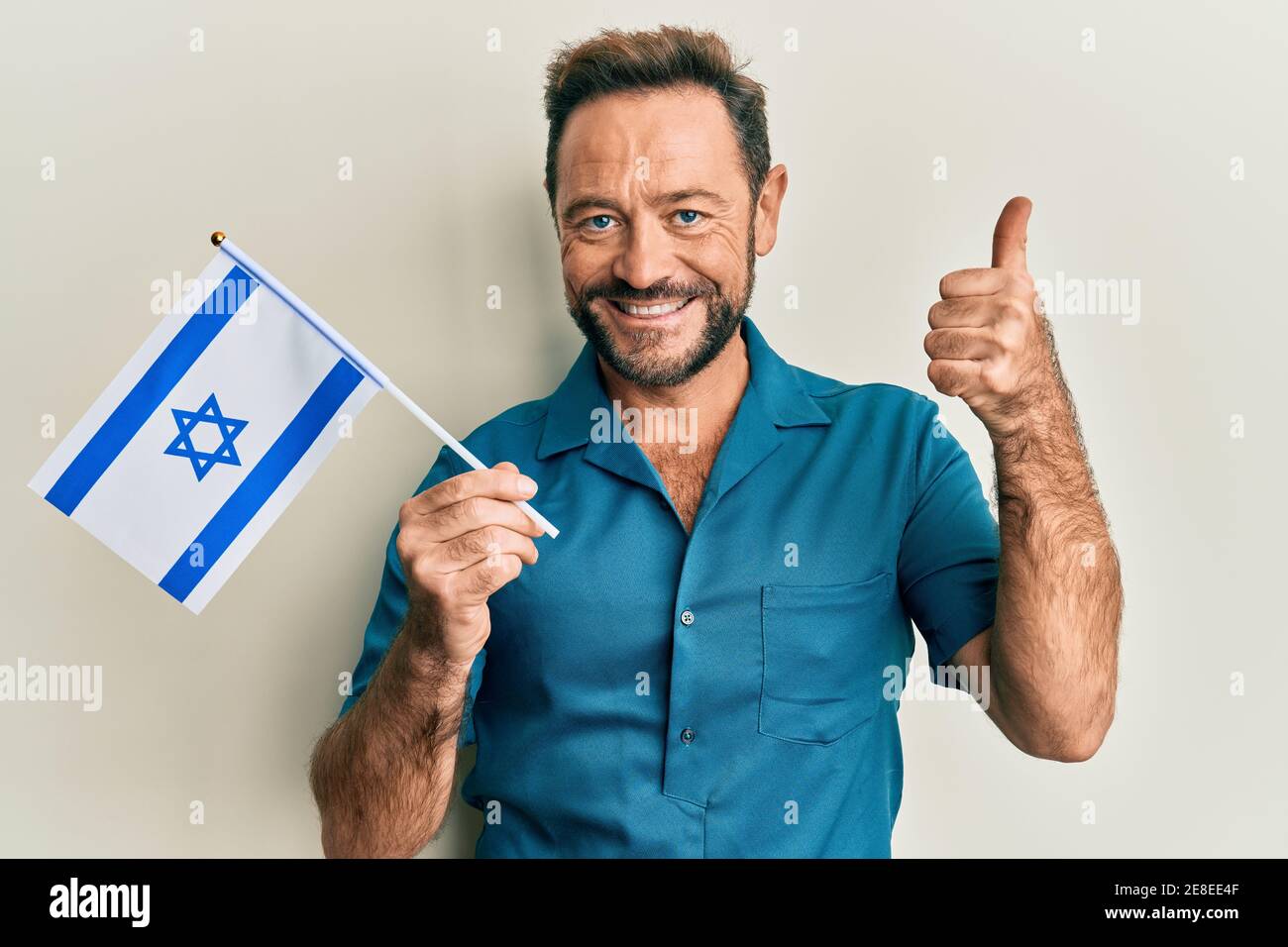 Middle age man holding israel flag smiling happy and positive, thumb up ...