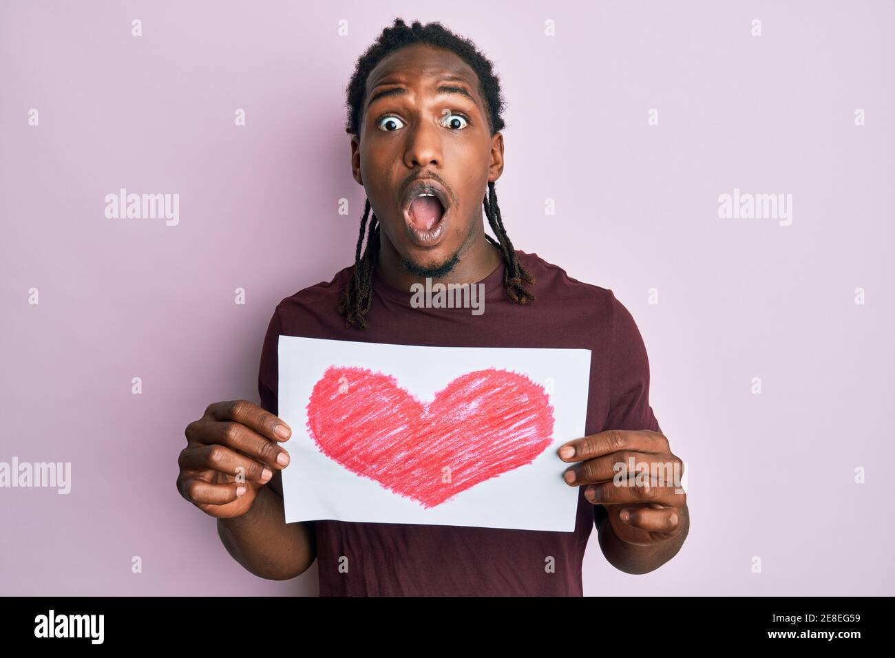 African american man with braids holding heart draw afraid and shocked ...