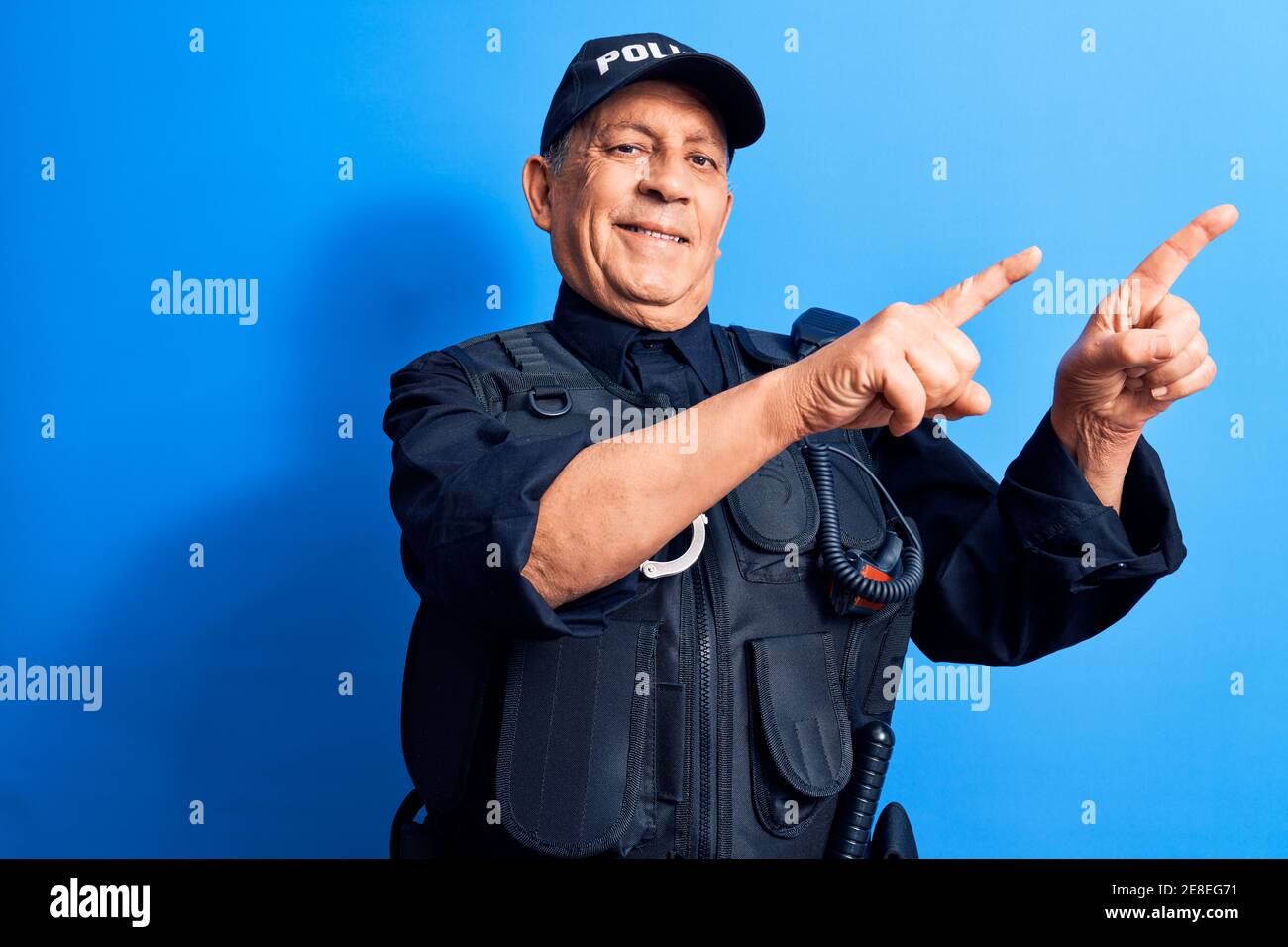 Senior man with grey hair wearing police uniform smiling and looking at ...