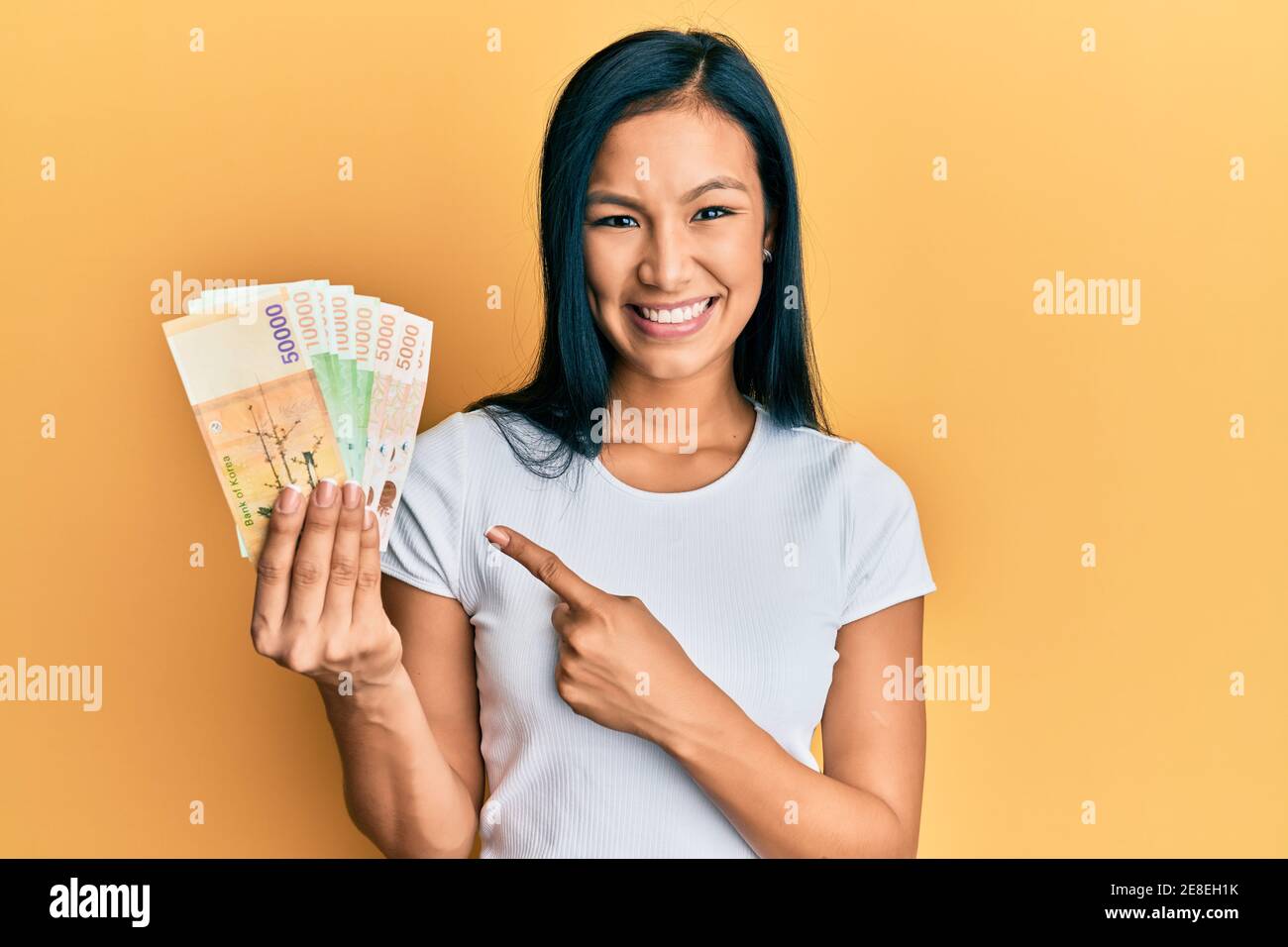 Beautiful hispanic woman holding south korean won banknotes smiling ...