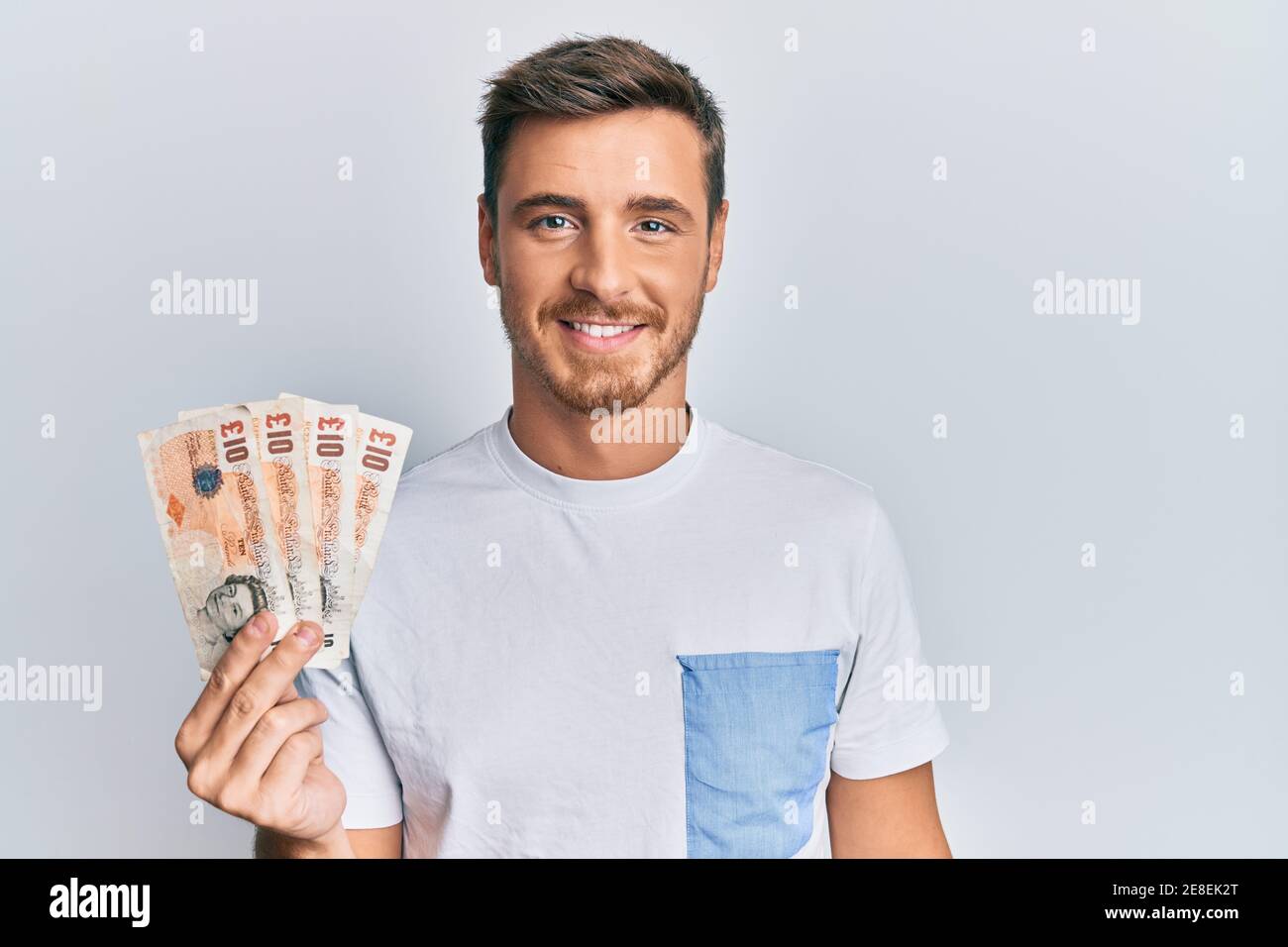 Handsome caucasian man holding 10 united kingdom pounds banknotes ...
