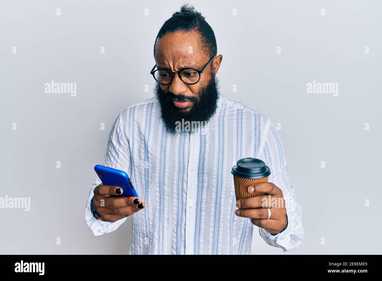 Young african american man using smartphone and drinking a cup of ...