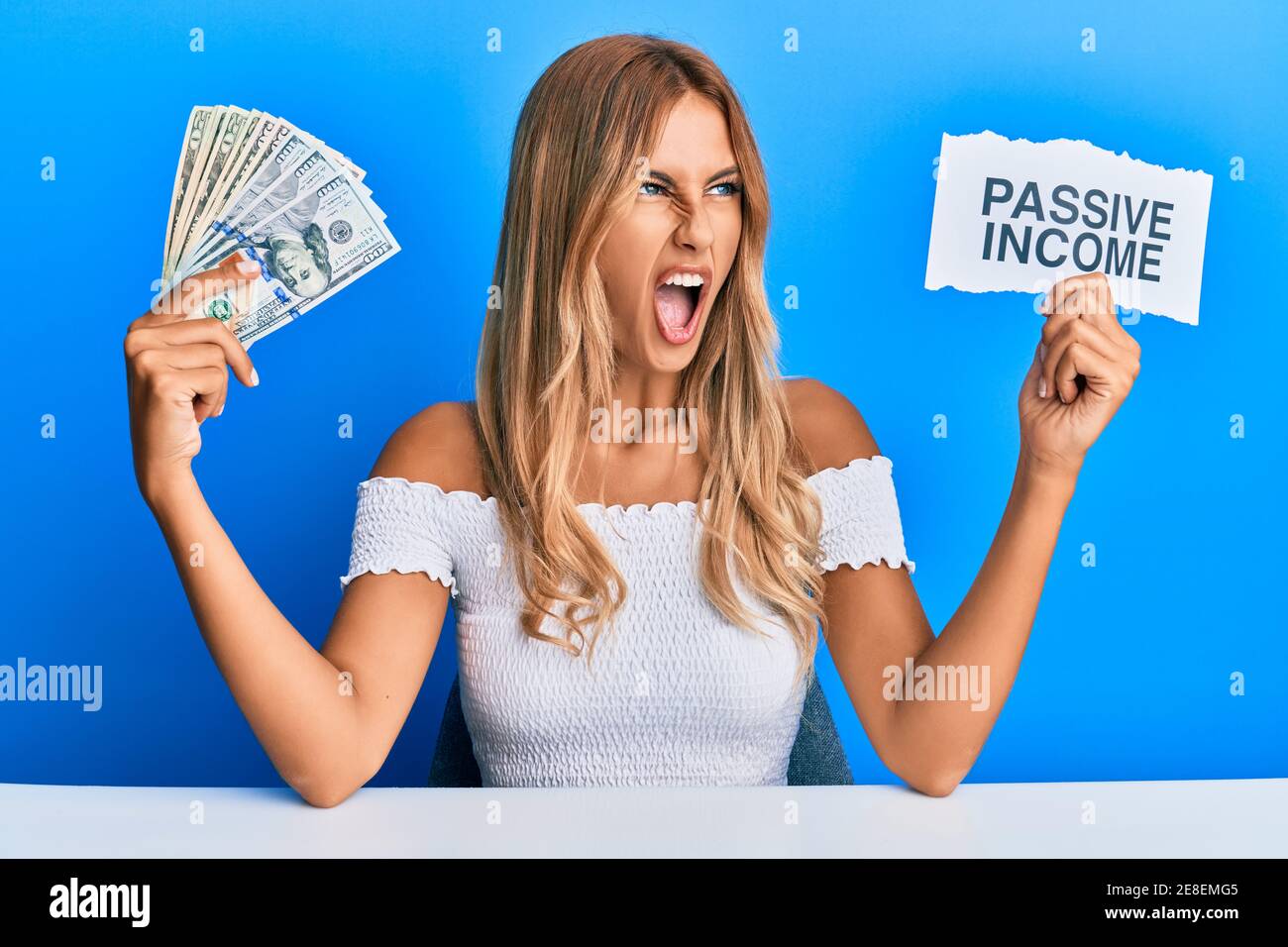 Beautiful blonde young woman holding dollars and passive income text ...