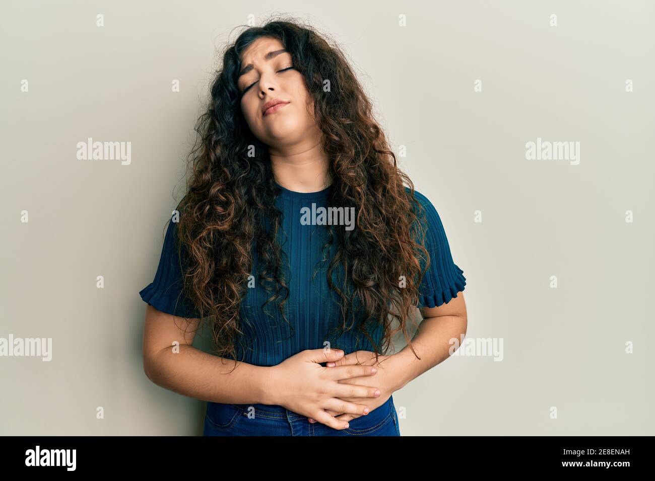 Young brunette woman with curly hair wearing casual clothes with hand ...
