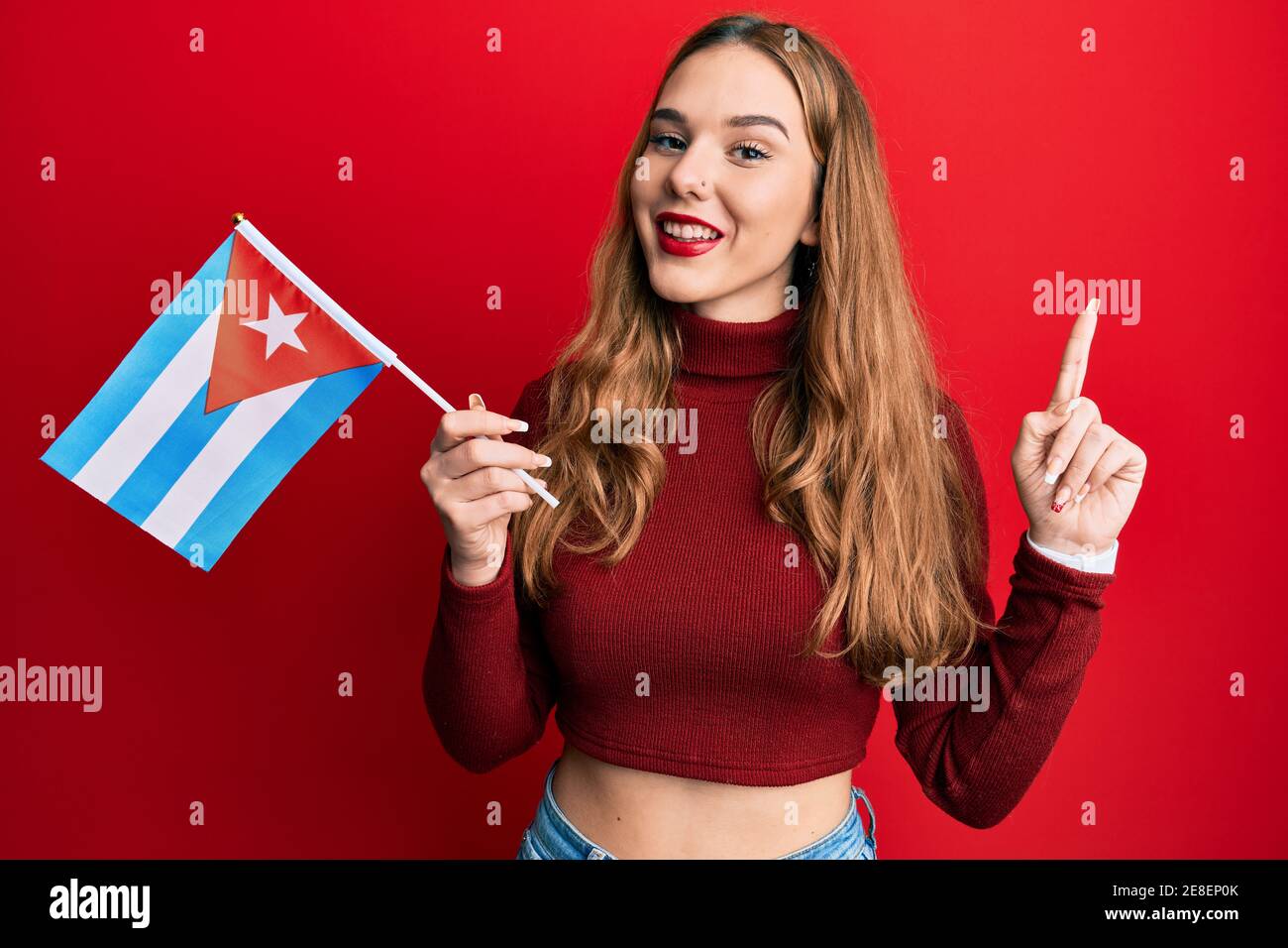 Young blonde woman holding cuba flag smiling with an idea or question ...