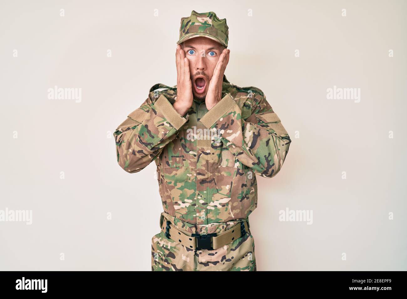Young caucasian man wearing camouflage army uniform afraid and shocked ...
