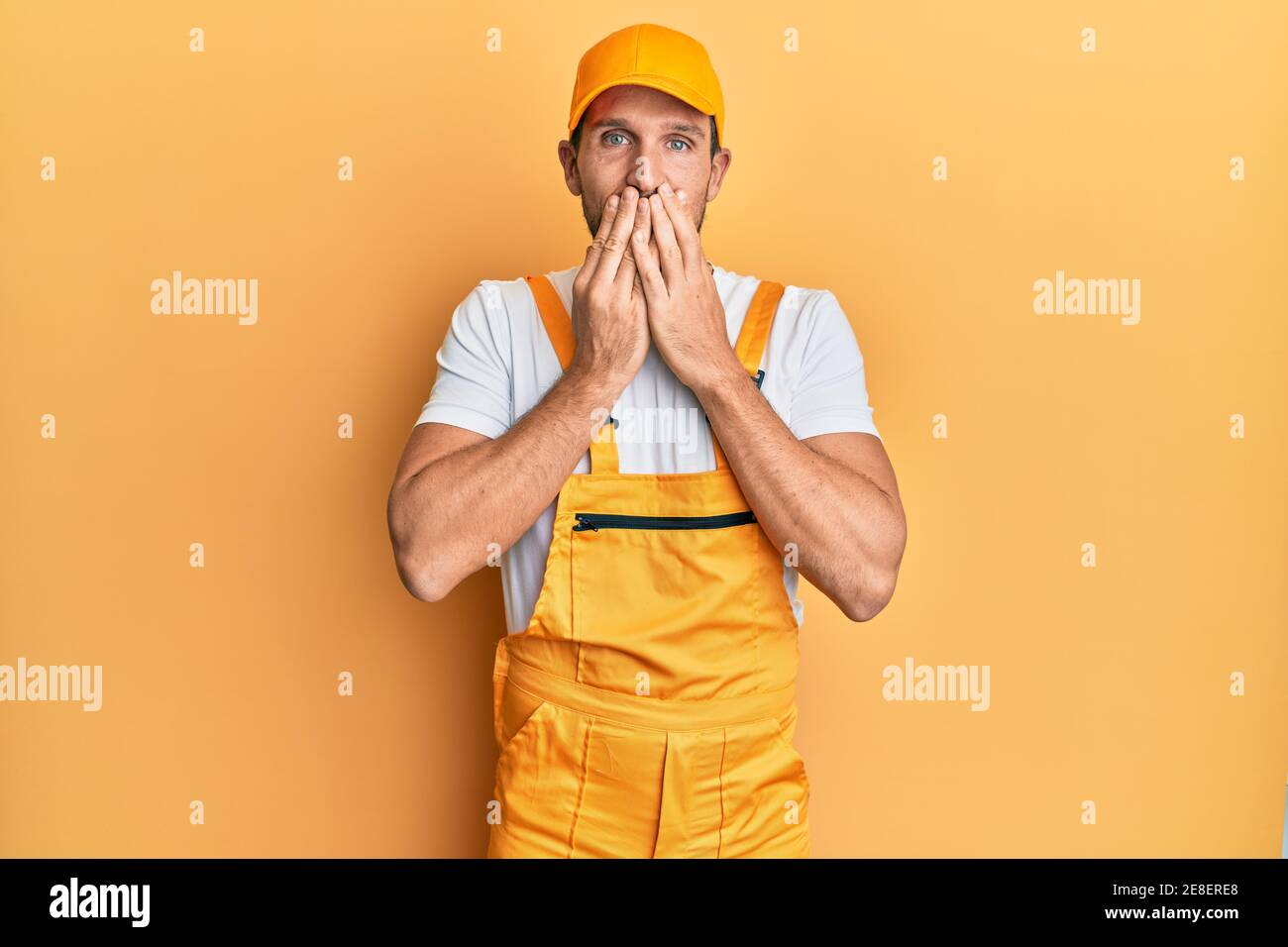 Young handsome man wearing handyman uniform over yellow background ...