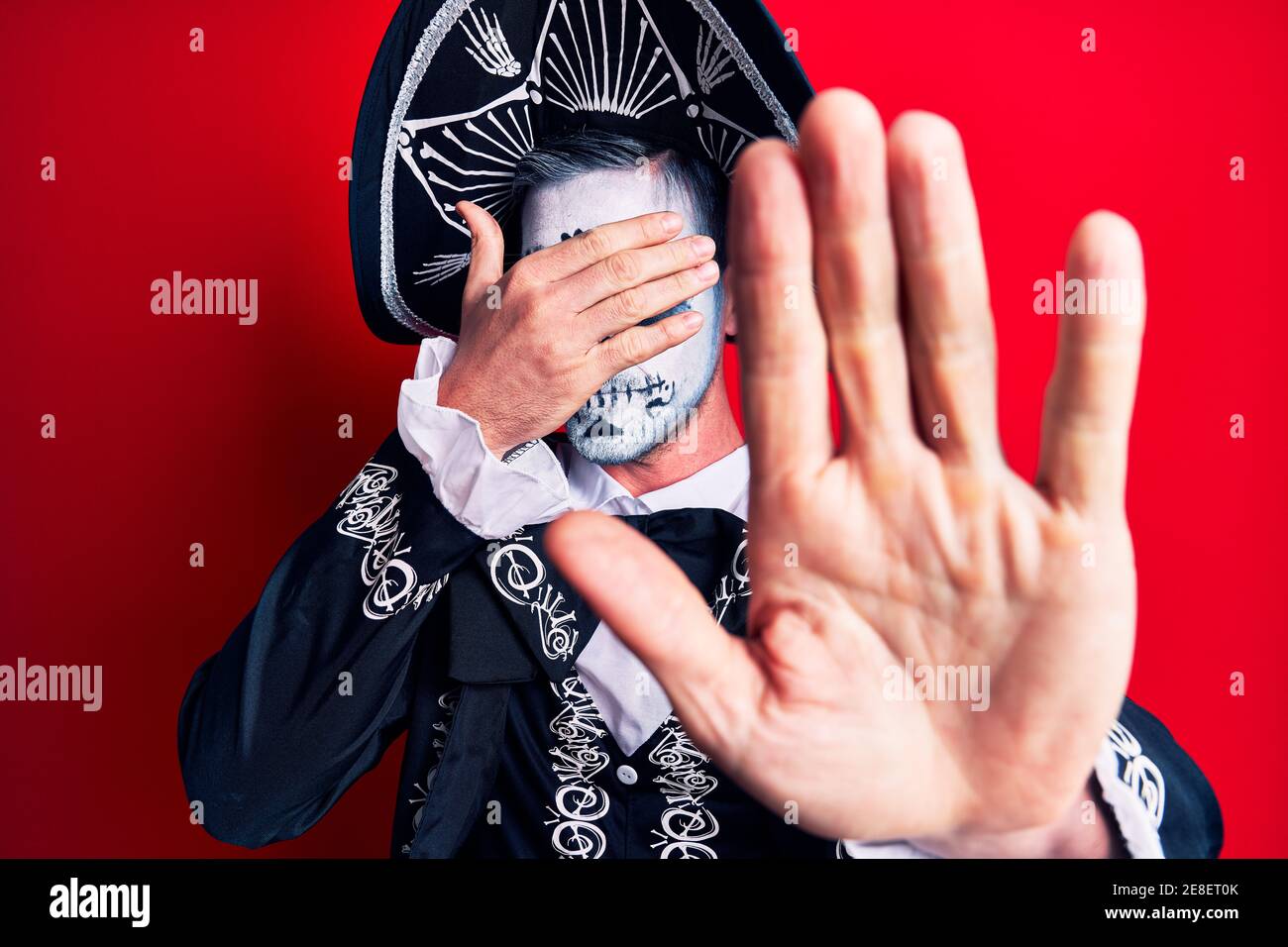 Young man wearing mexican day of the dead costume over red covering ...