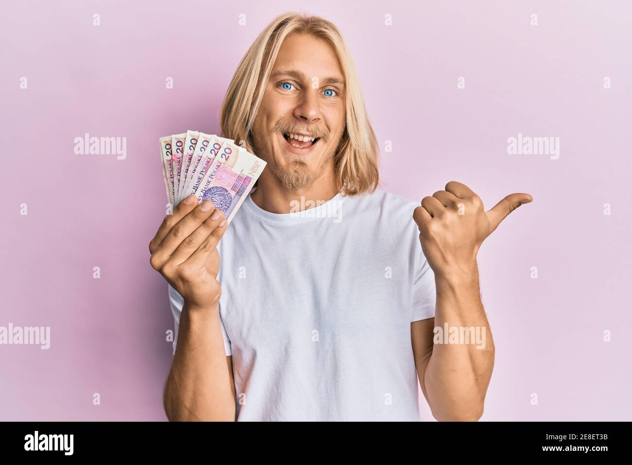 Caucasian young man with long hair holding 20 polish zloty banknotes ...