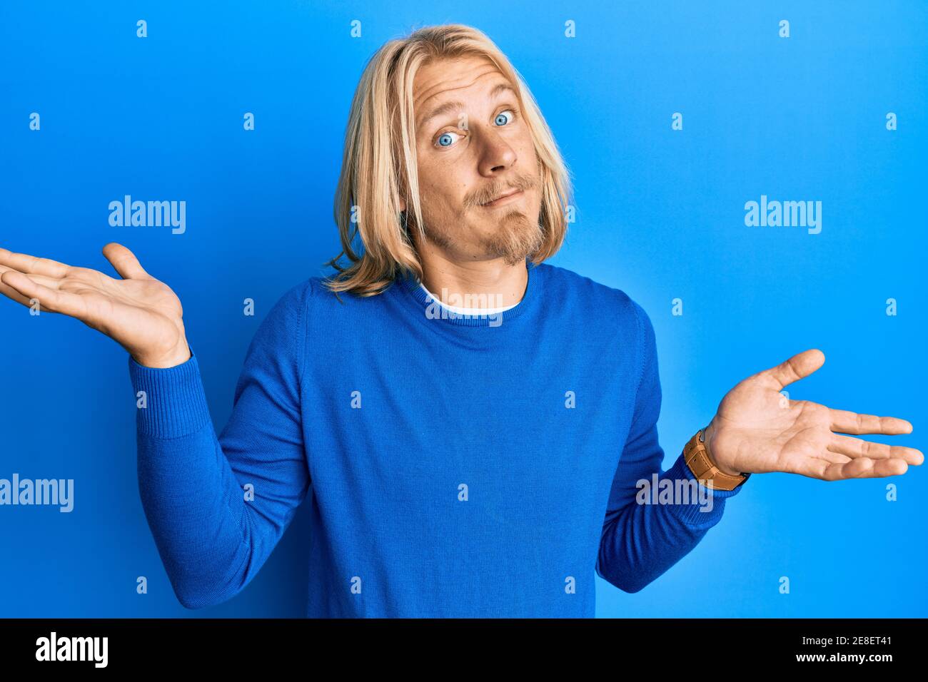 Caucasian young man with long hair wearing casual clothes clueless and ...