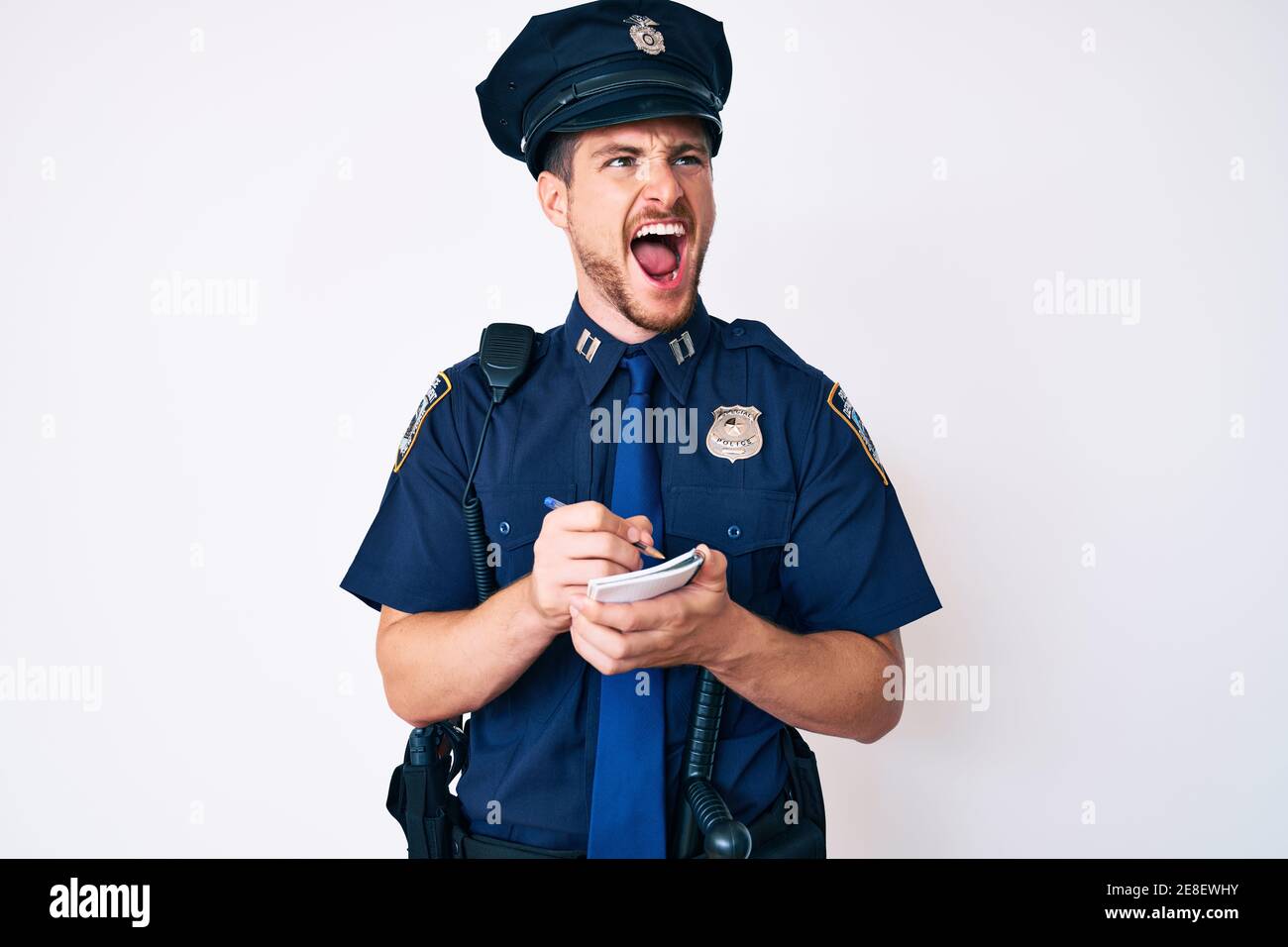 Young caucasian man wearing police uniform writing fine angry and mad ...