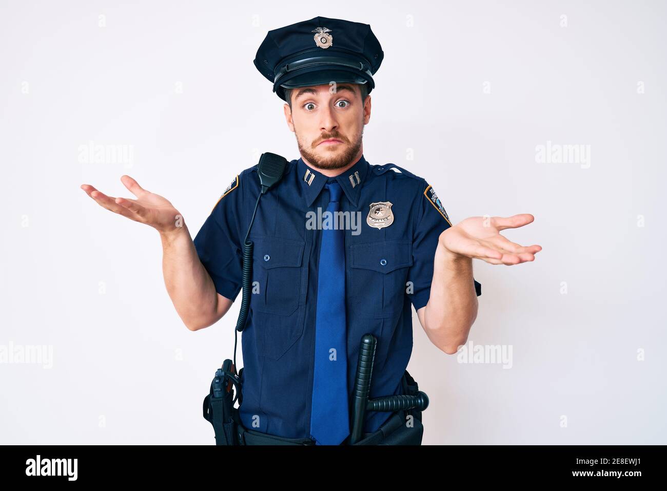 Young caucasian man wearing police uniform clueless and confused ...