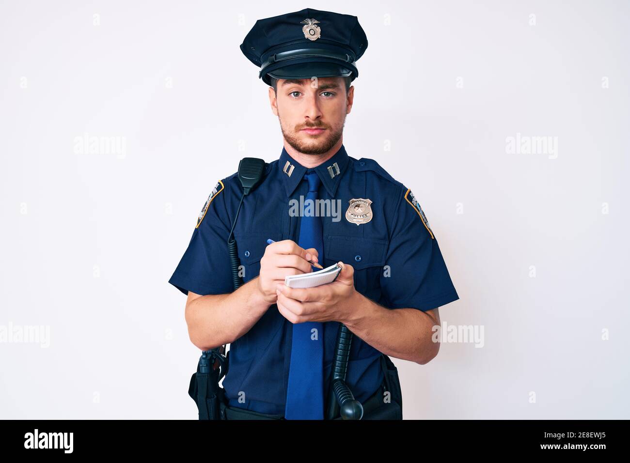 Young caucasian man wearing police uniform writing fine skeptic and ...