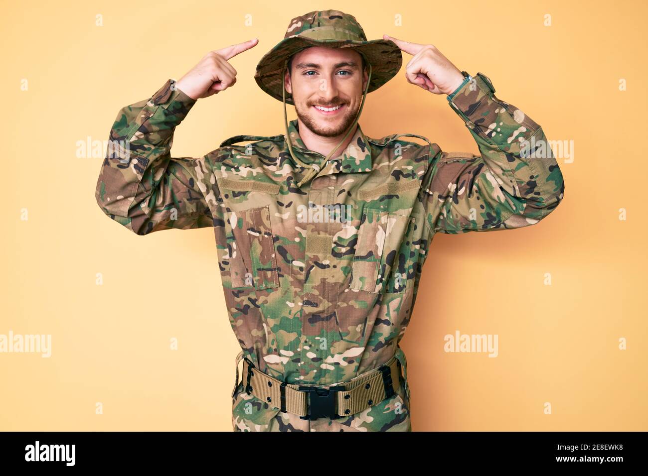 Young caucasian man wearing camouflage army uniform smiling pointing to ...