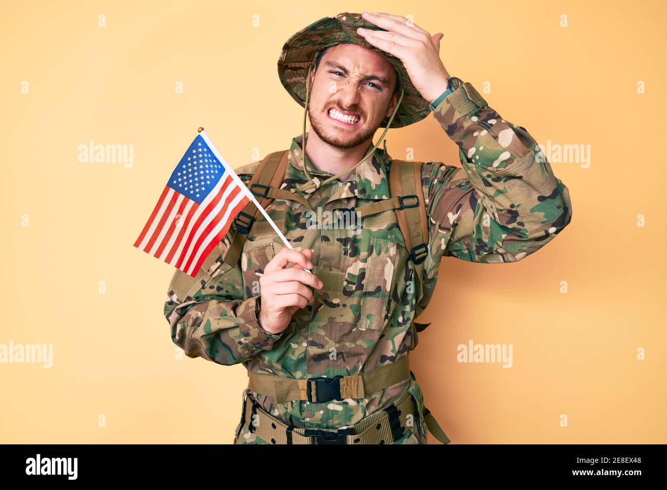 Young caucasian man wearing camouflage army uniform holding usa flag ...