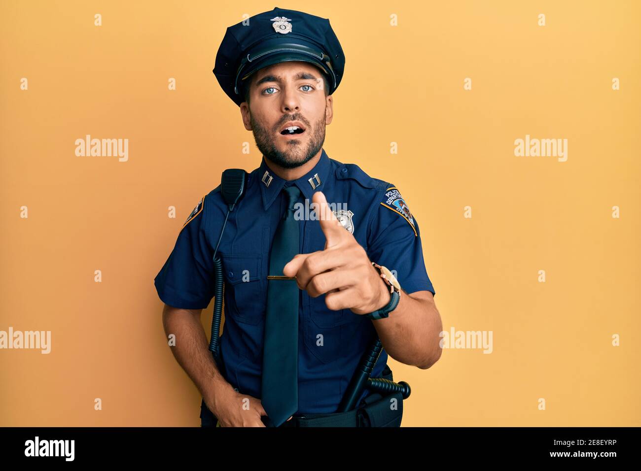 Handsome hispanic man wearing police uniform pointing displeased and ...
