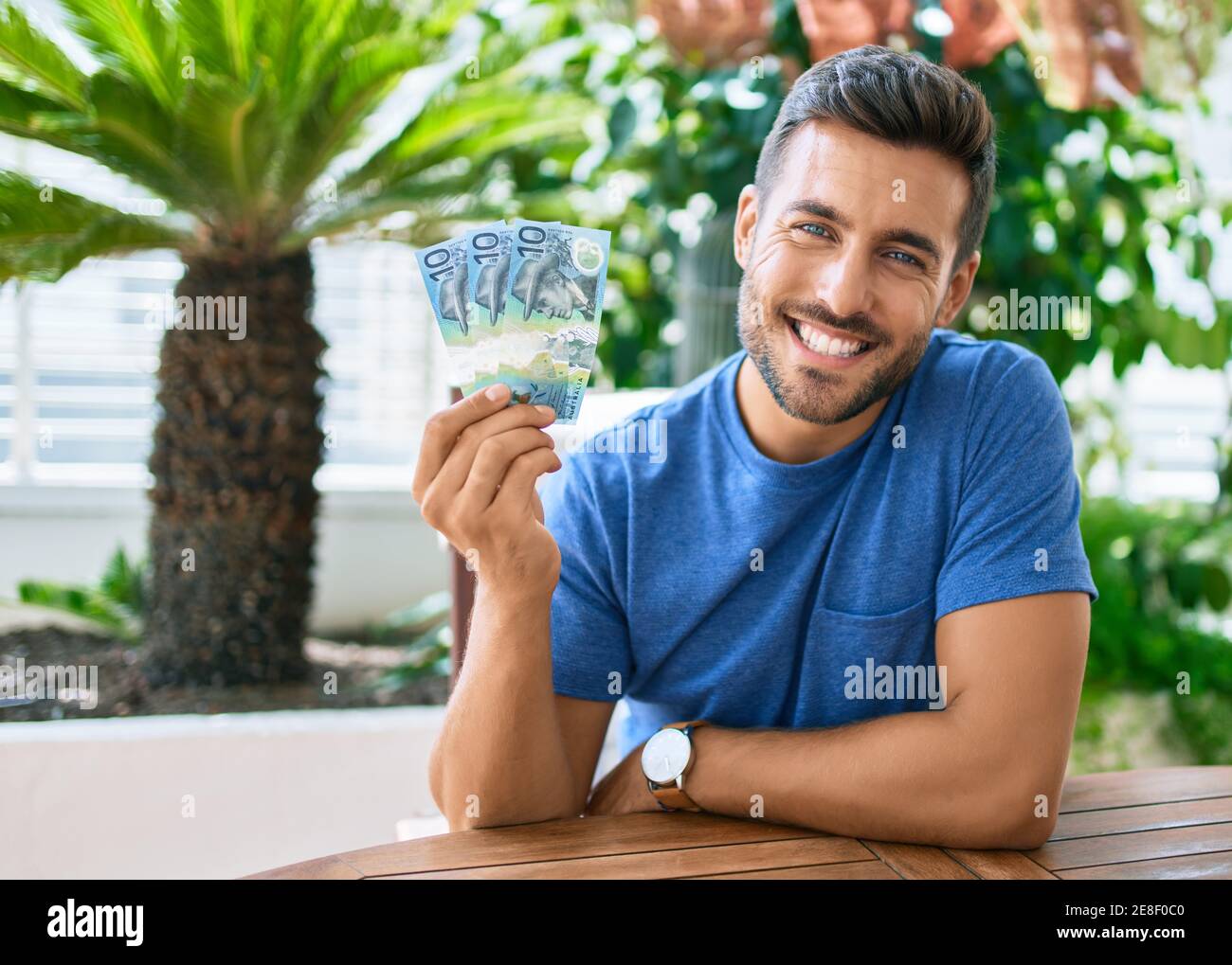 Young hispanic man smiling happy holding australian dollars banknotes ...