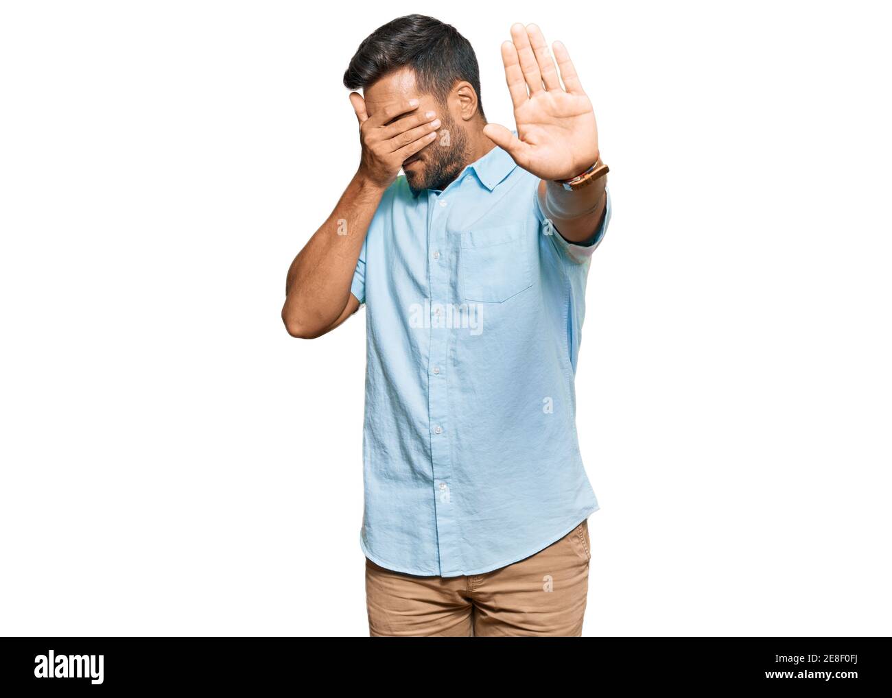 Handsome hispanic man wearing casual clothes covering eyes with hands ...