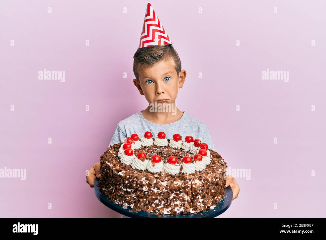 Adorable caucasian kid celebrating birthday with cake depressed and ...