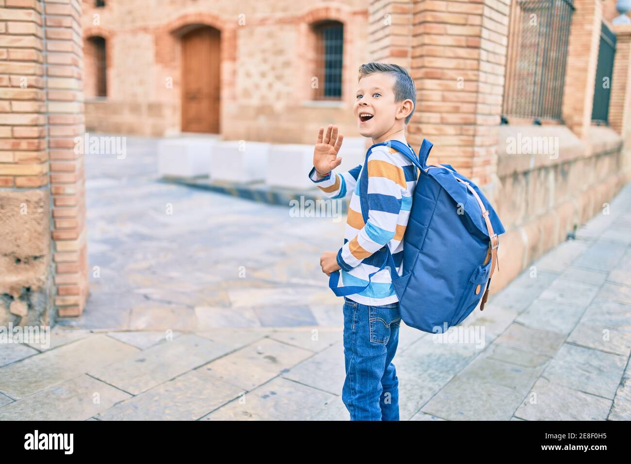 Adorable caucasian student boy smiling happy saying goodbye with hand ...