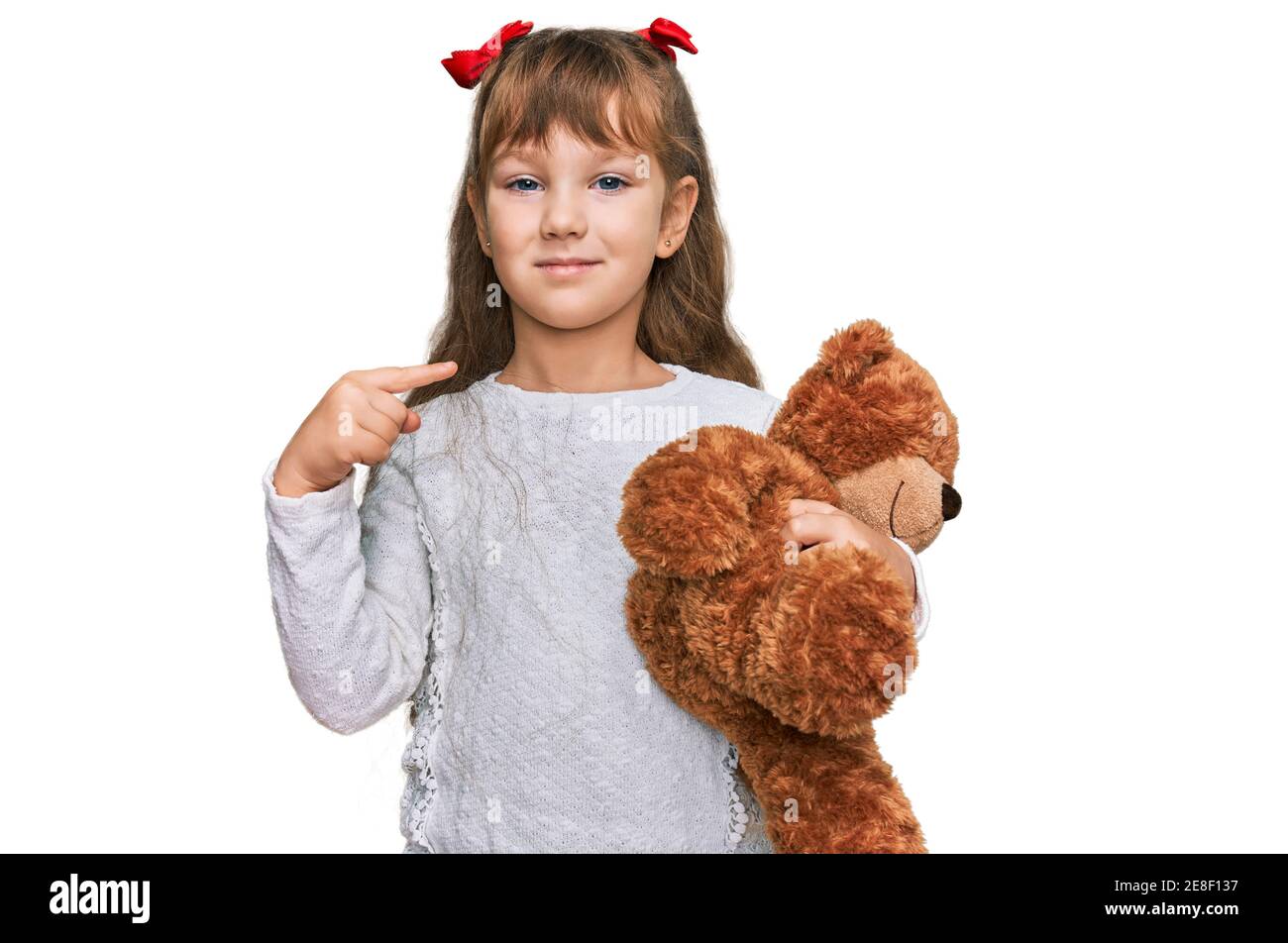 Little caucasian girl kid hugging teddy bear stuffed animal pointing ...