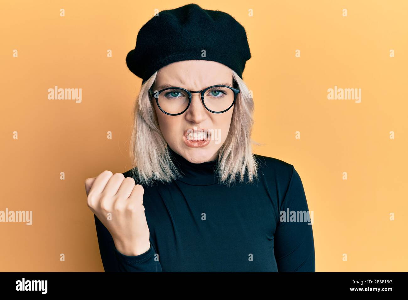 Young blonde girl wearing french look with beret angry and mad raising ...