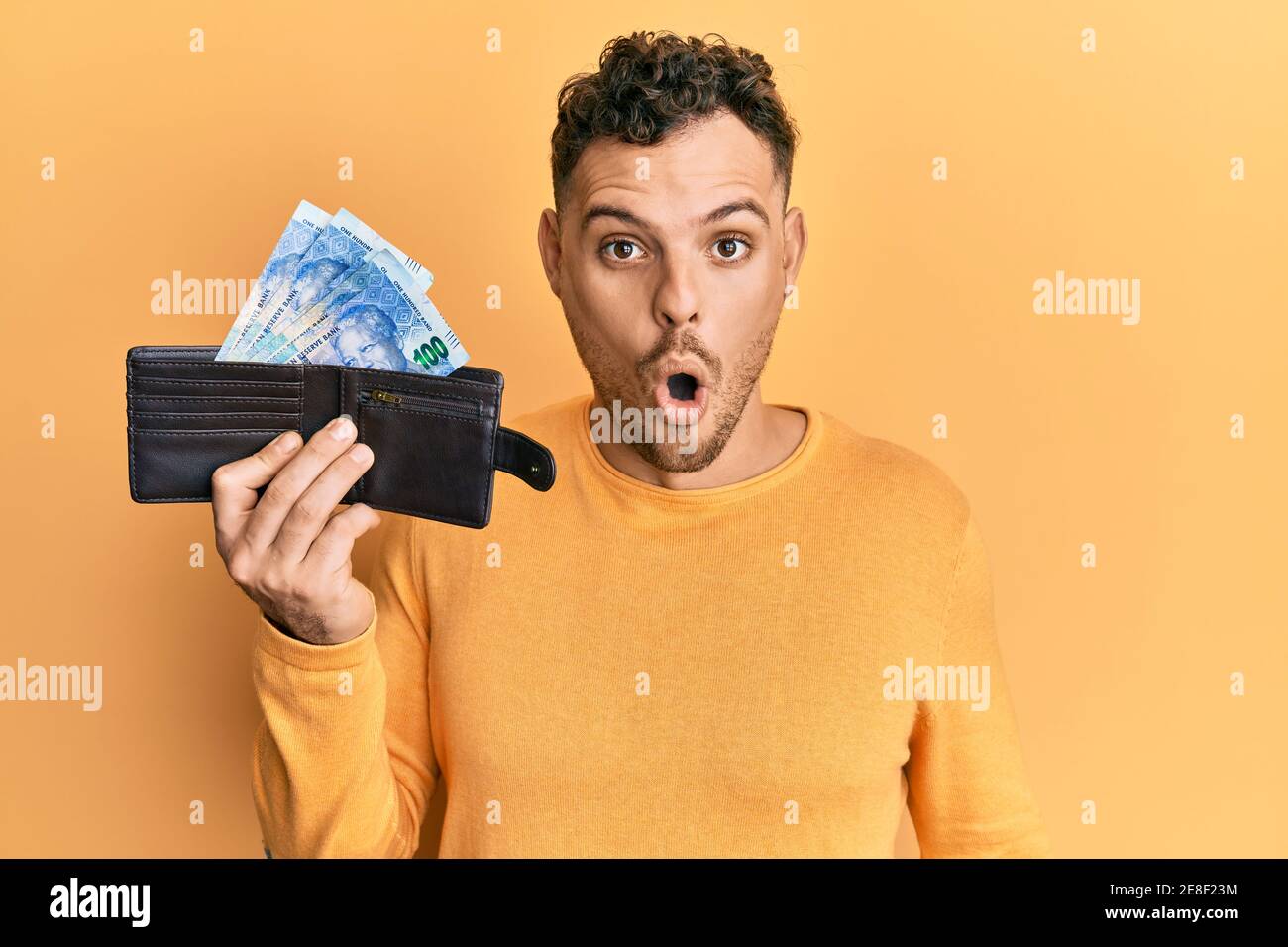 Young hispanic man holding wallet with south african rand banknotes ...