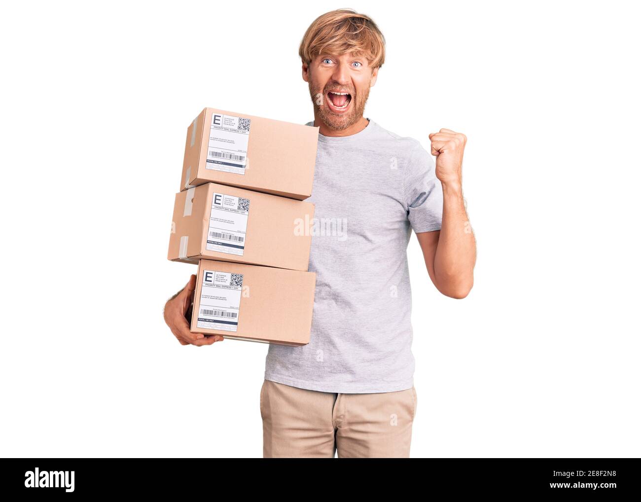 Handsome caucasian man with beard holding delivery packages screaming ...