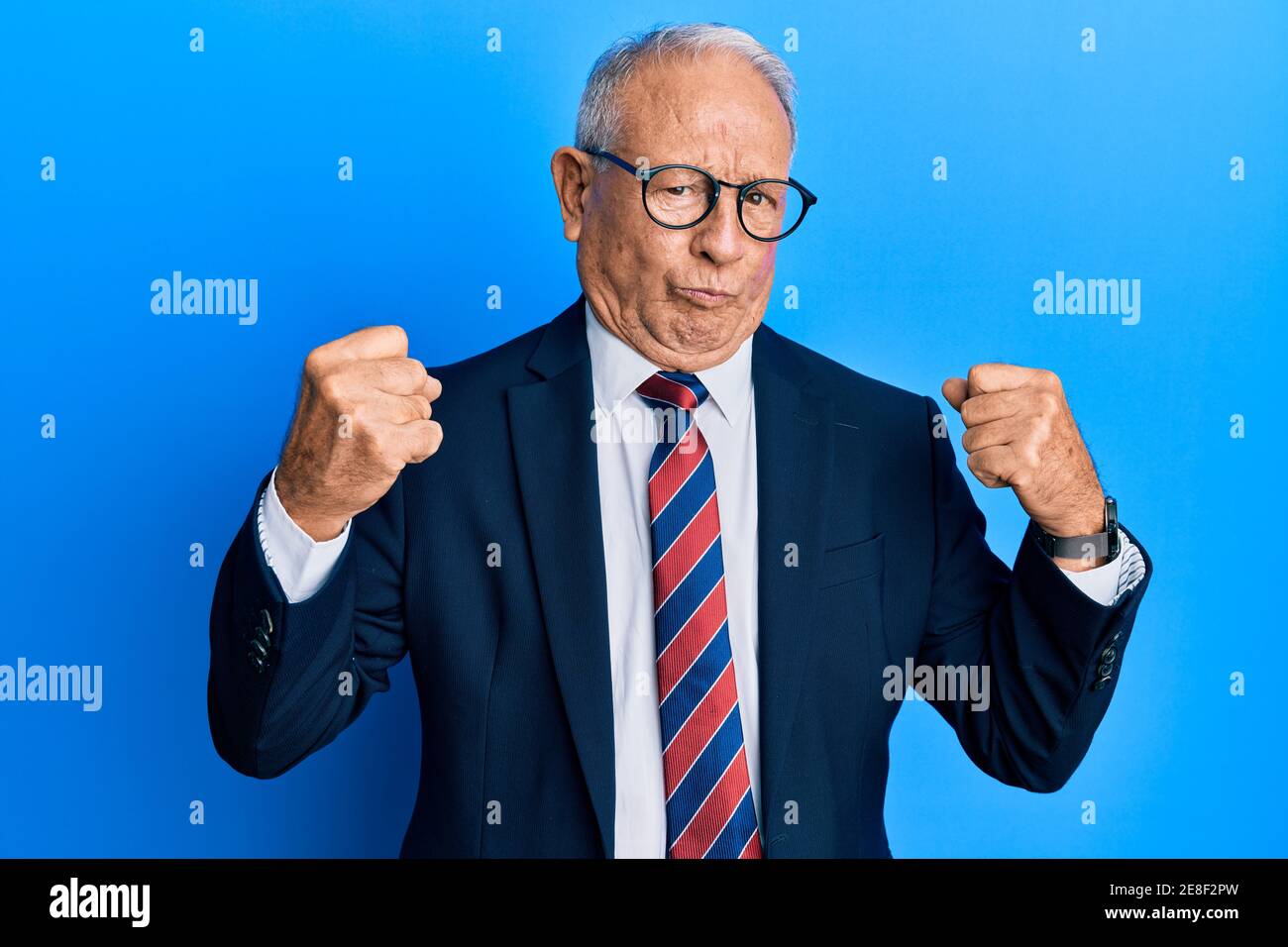 Senior caucasian man wearing business suit and tie showing arms muscles ...