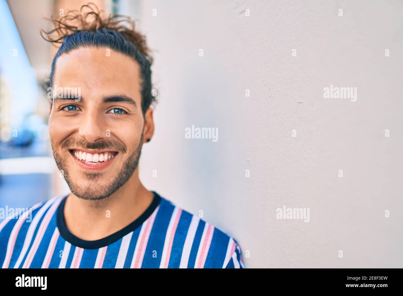 Young hispanic man smiling happy looking to the camera leaning on the ...