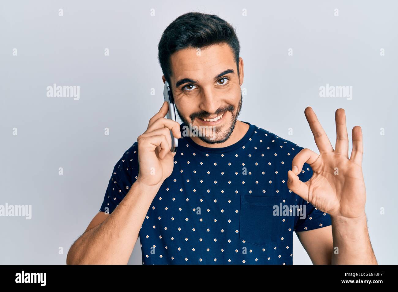 Young hispanic man having conversation talking on the smartphone doing ...
