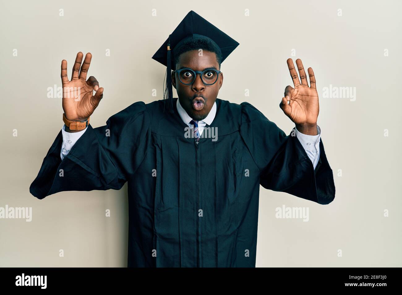 Handsome black man wearing graduation cap and ceremony robe looking ...