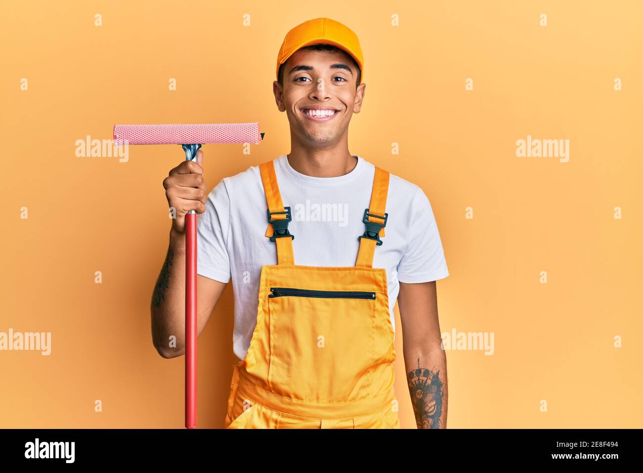 Young handsome african american man window cleaner holding glass washer ...