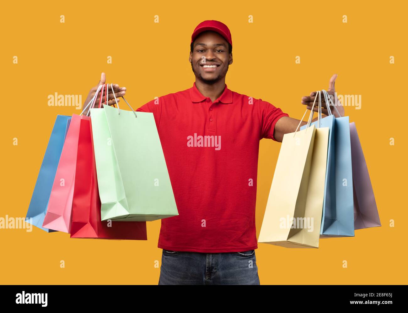 Black delivery guy holding colorful bags at studio Stock Photo - Alamy