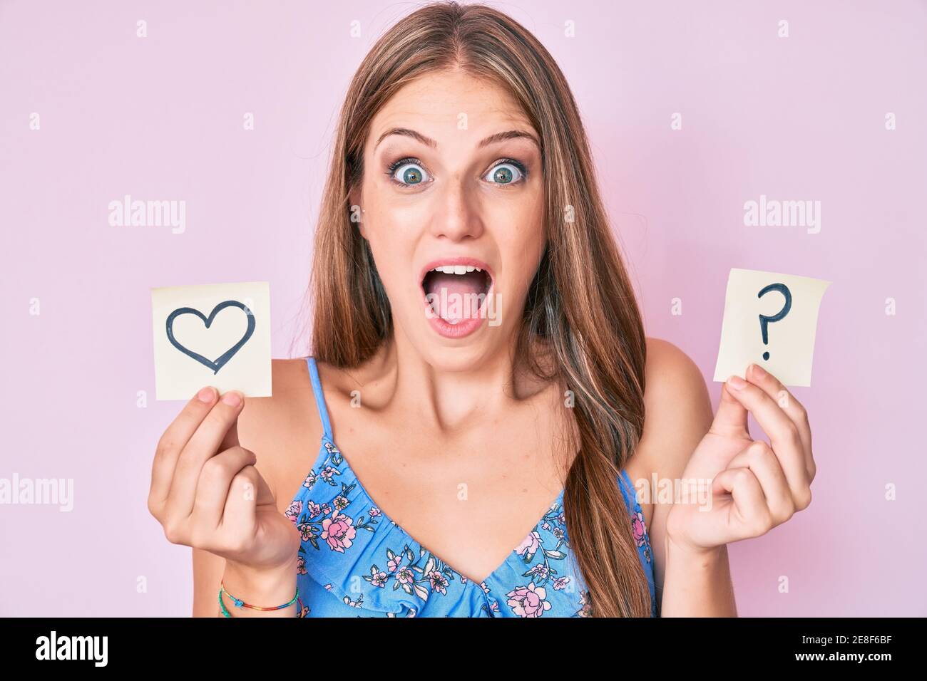 Young blonde girl holding heart and question mark reminder celebrating ...